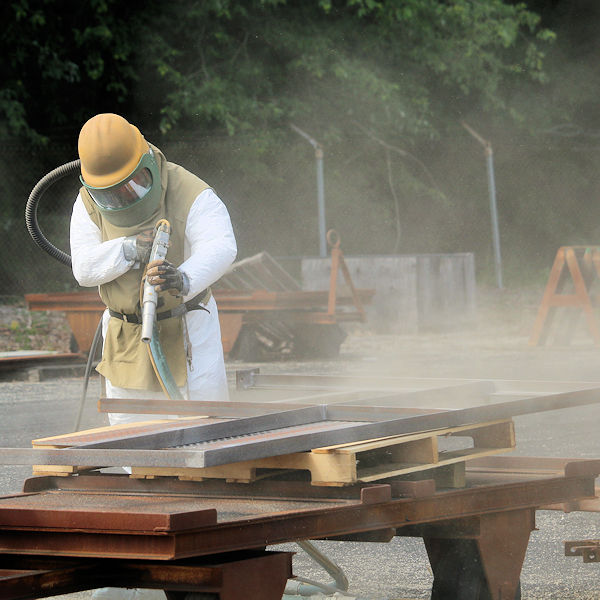 Worker sandblasting metal